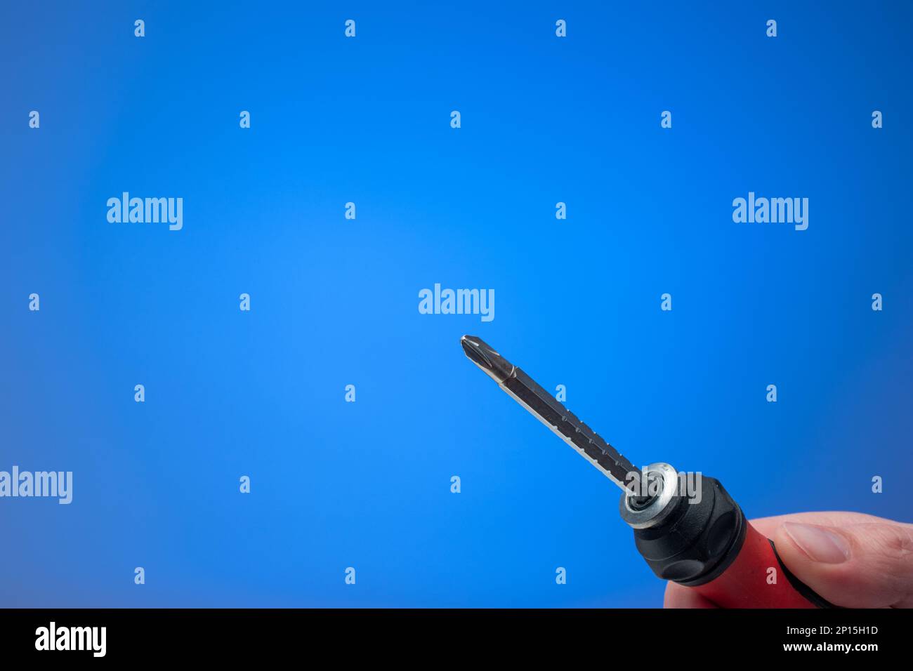 Turn screwdriver in man's hand. Close up studio shot, isolated on blue ...