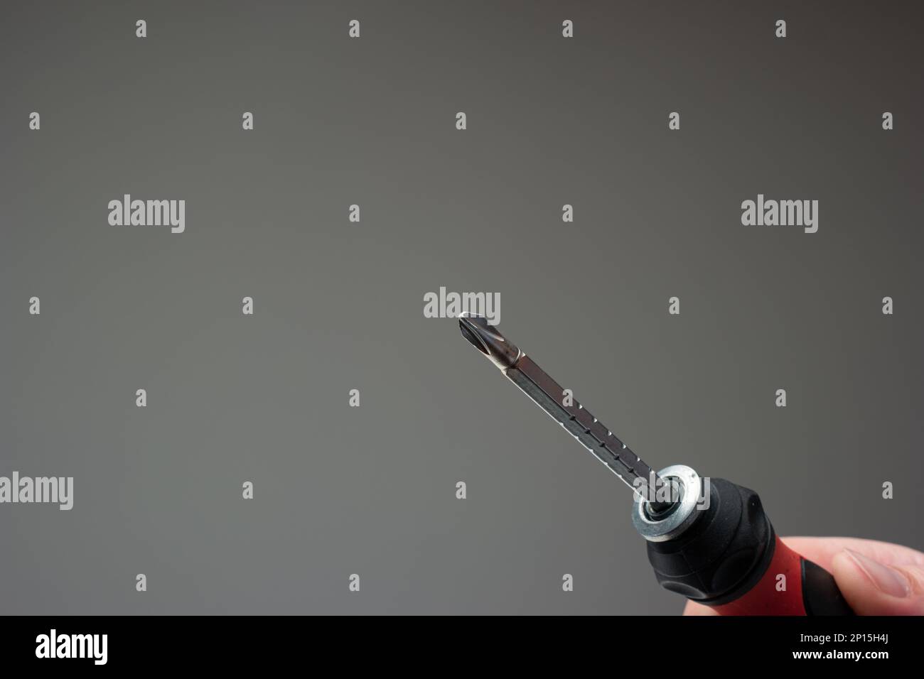 Turn screwdriver in man's hand. Close up studio shot, isolated on gray ...