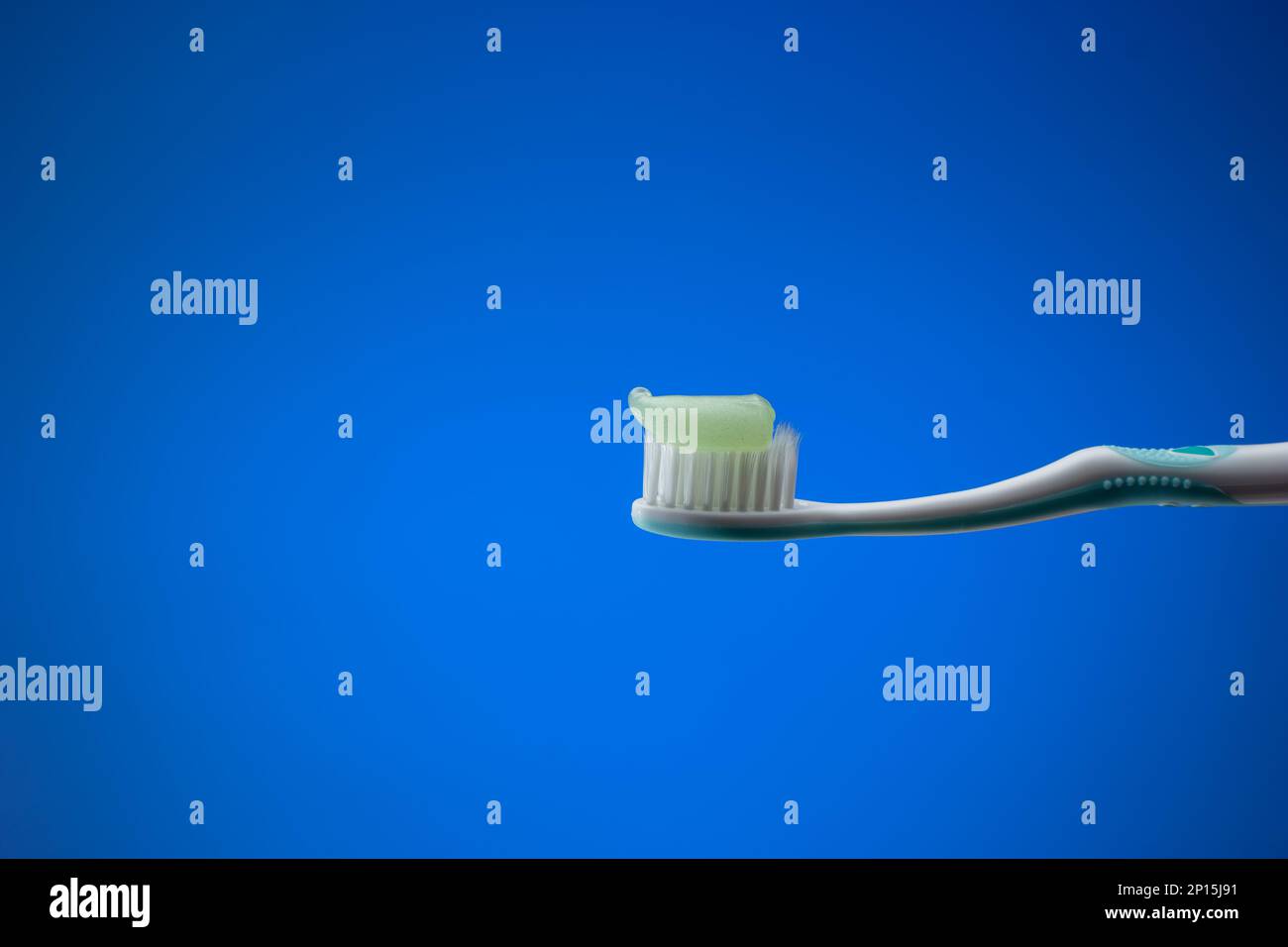White plastic toothbrush with light blue toothpaste. Close up studio ...