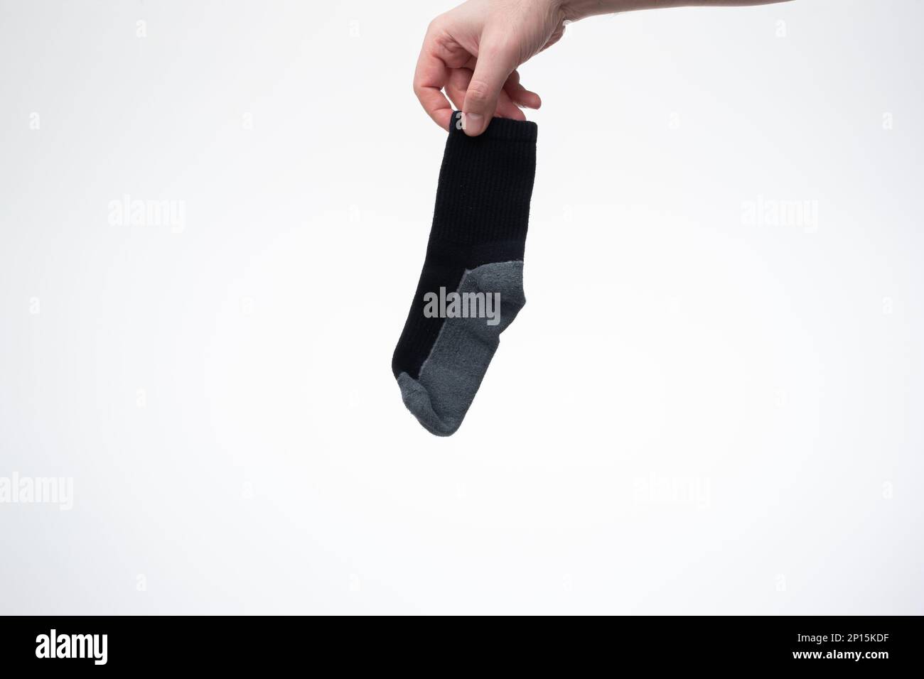 Single dry and clean cotton sock held in hand by Caucasian male hand ...
