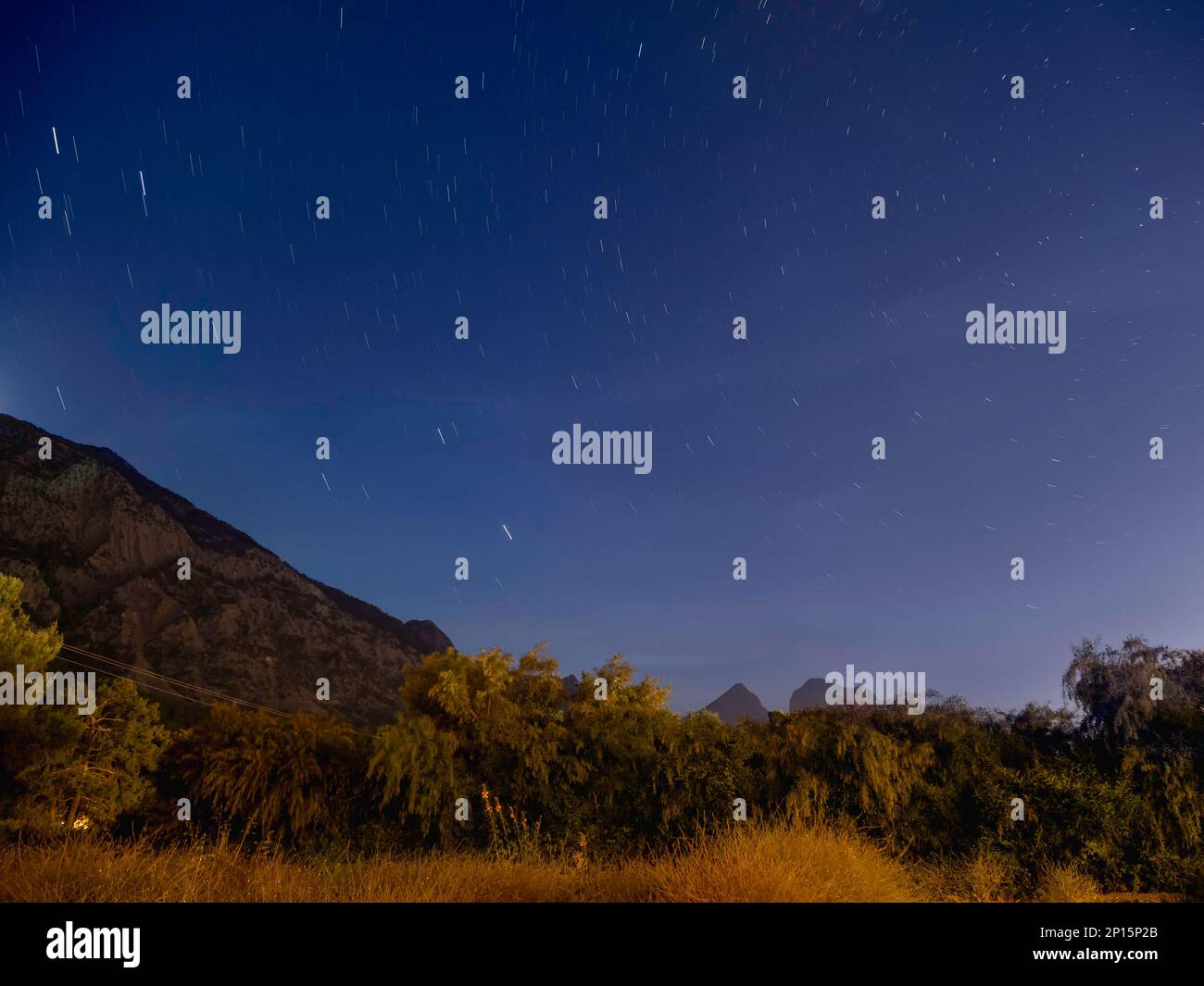 Traces of stars moving in the night sky upon mountains in Beldibi ...