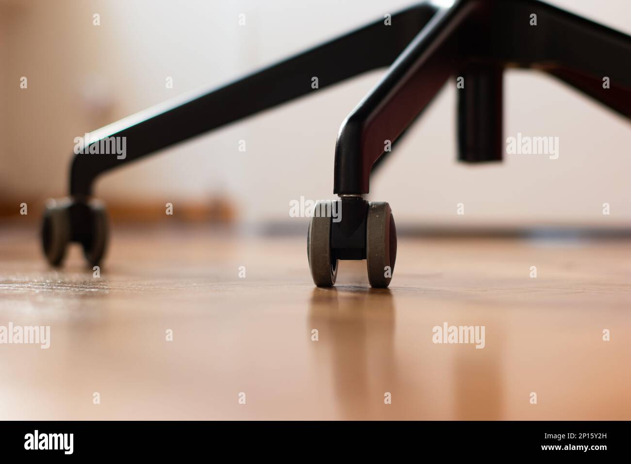 Black metal office chair lags with swivel wheels on wood floor tiling ...