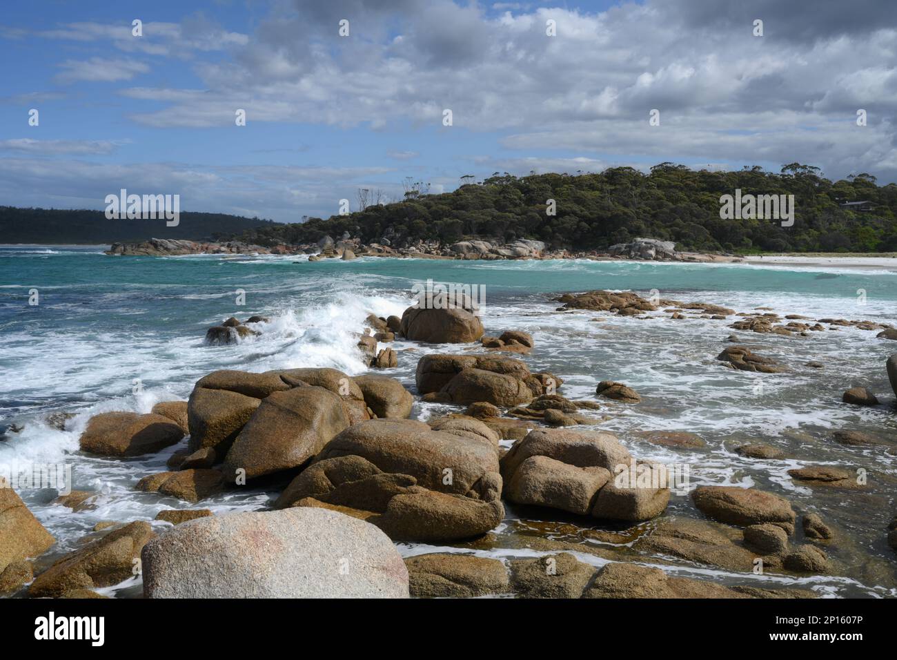 Wave breaking over boulders at Jeanneret beach are highlighted by a ...