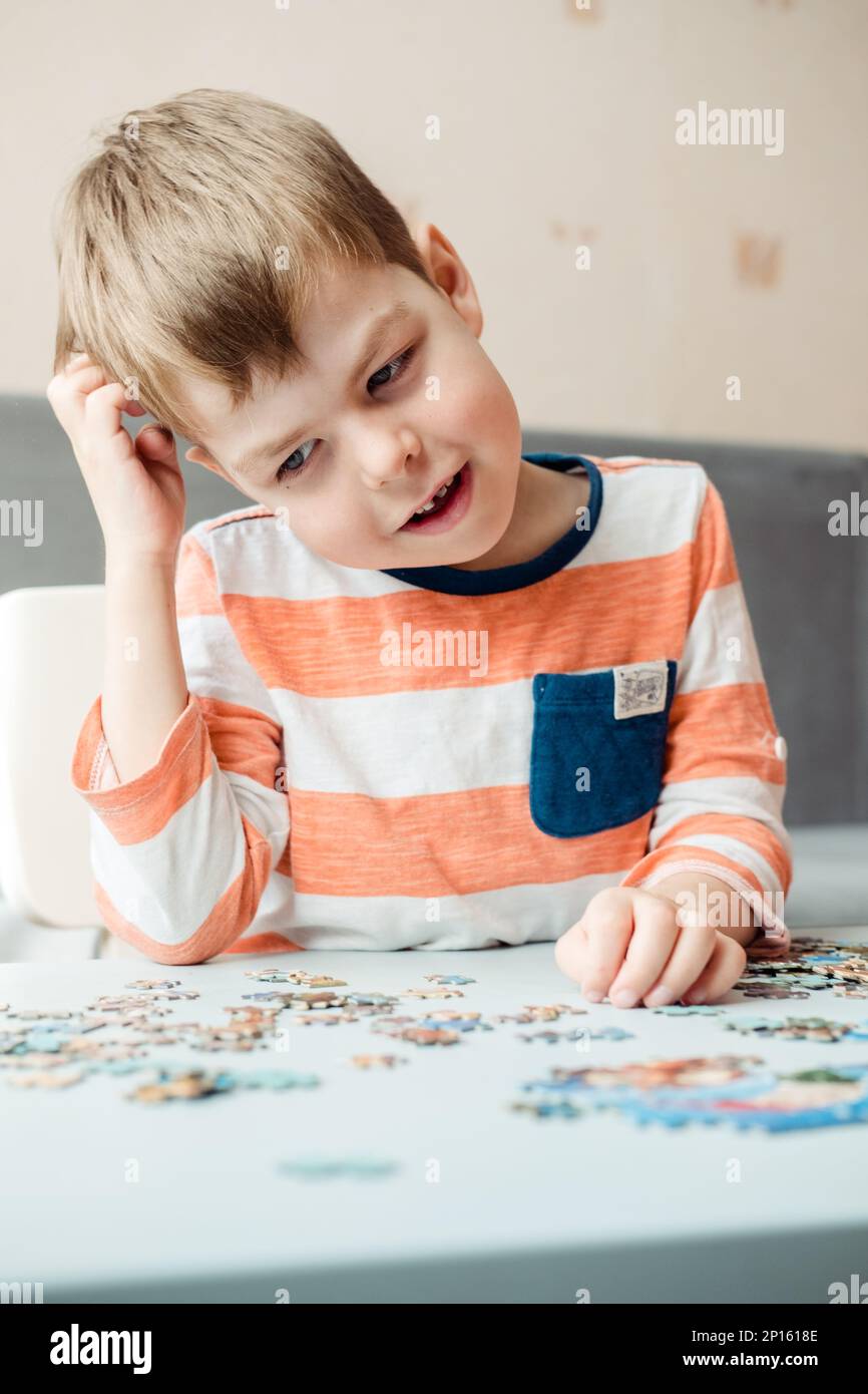 a 6-year-old boy collects a puzzle at home and holds his head ...