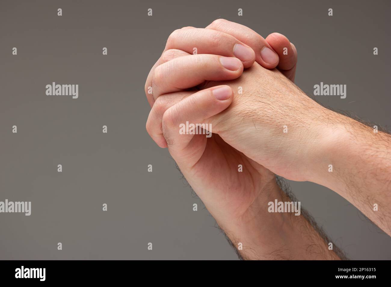 Caucasian male hands in prayer gesture isolated on gray background ...