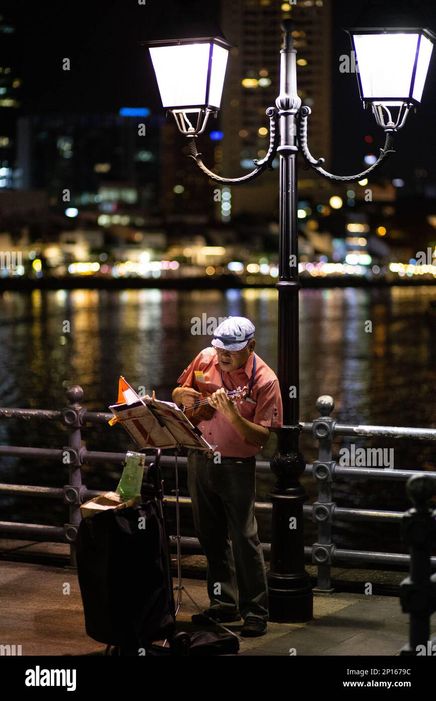 A man busking alongside the water front in Singapore Stock Photo - Alamy