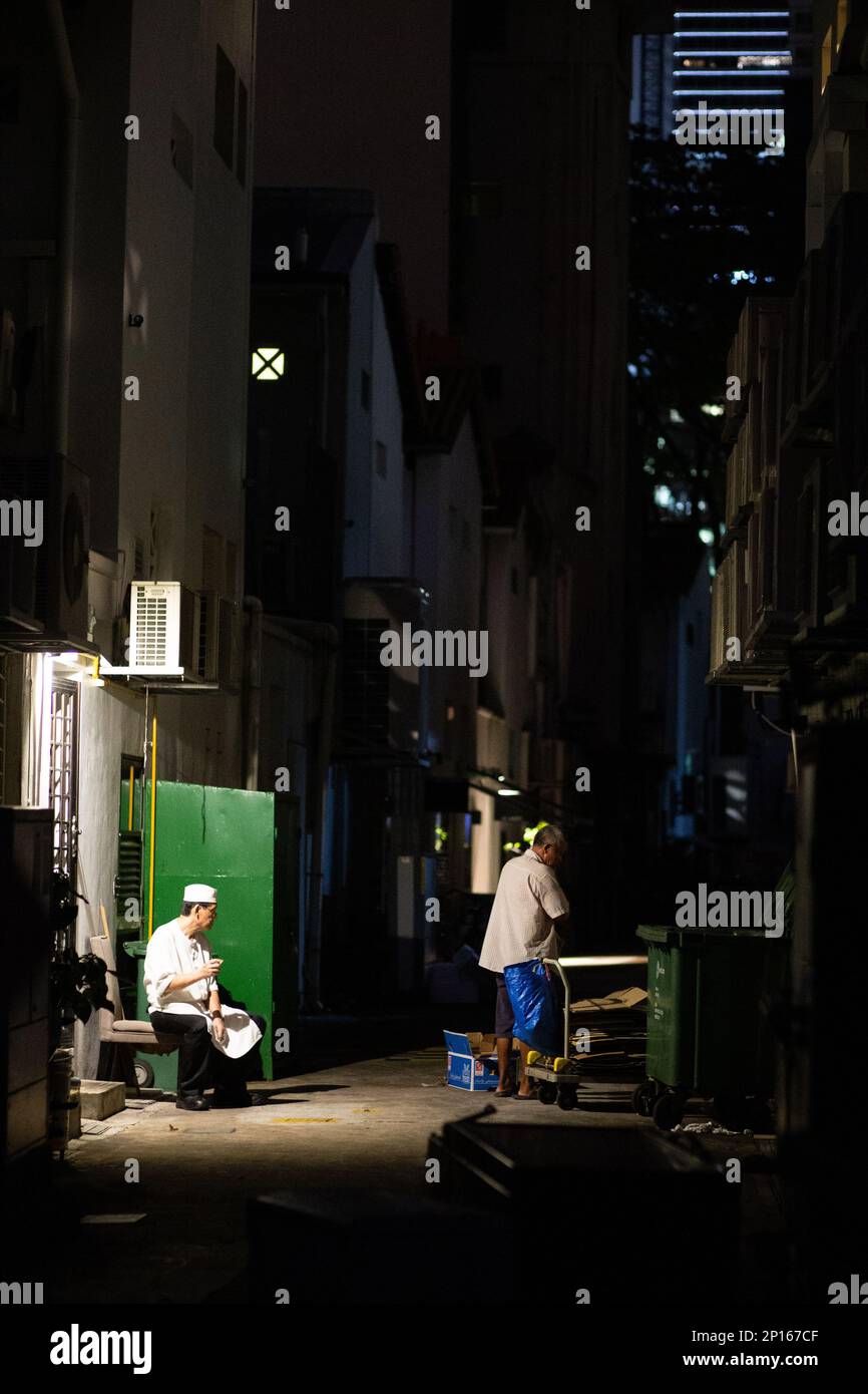 A chef and kitchen workers take a break in an alleyway , Singapore ...