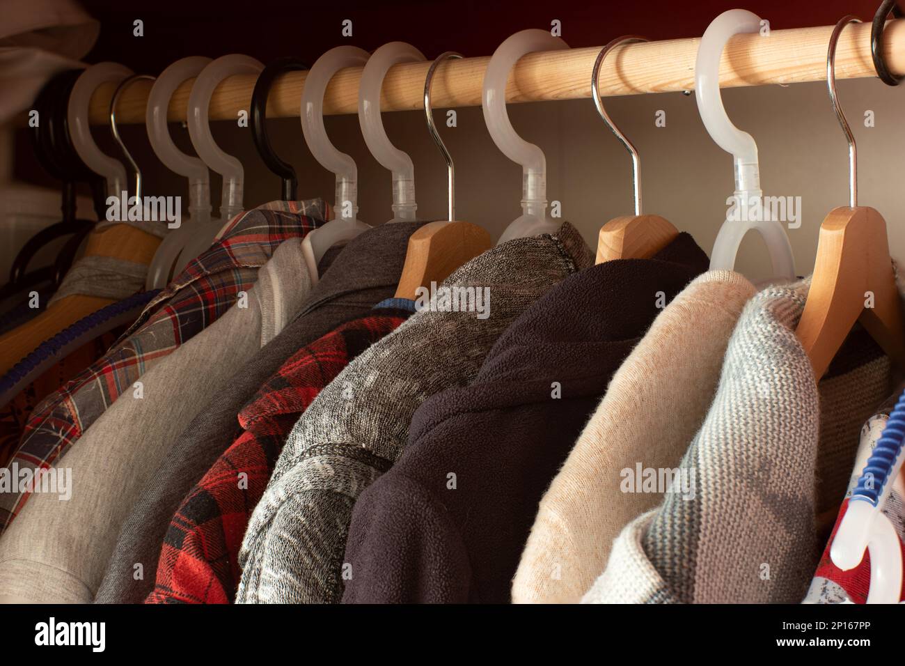 Row of various mix colored clothing items on hangers inside home closet ...