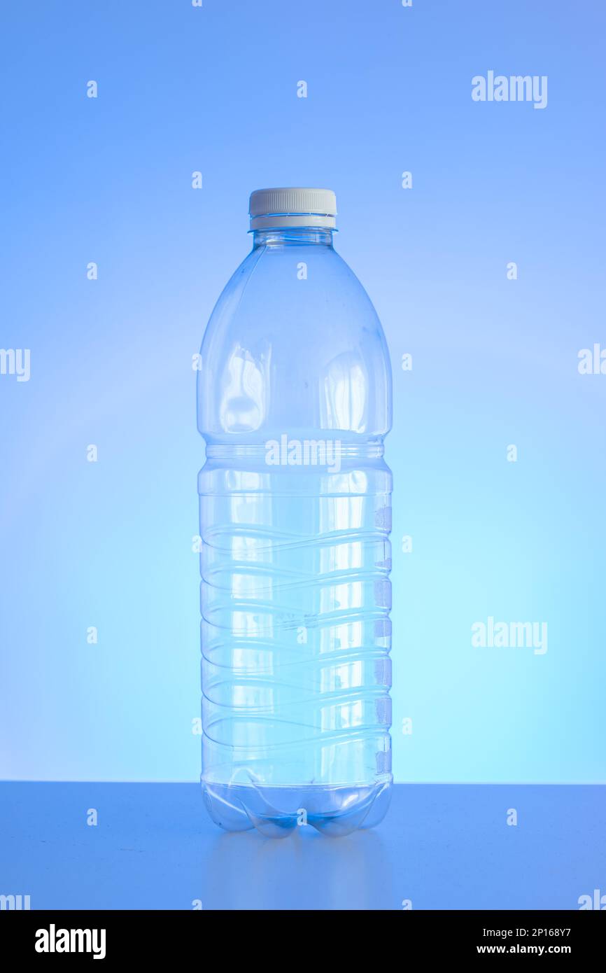 Clear empty plastic bottle with red lid isolated on light blue ...