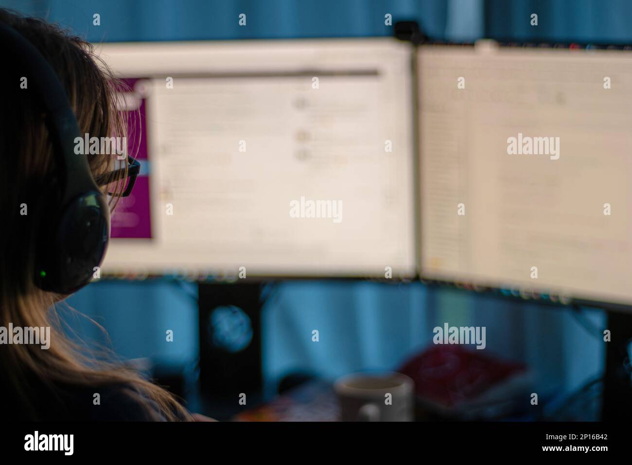 Unrecognizable woman with glasses working from home on two computer ...