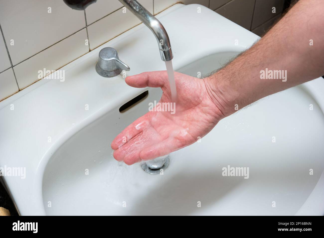 Bathroom Sink Tap Water Stream Flowing On Caucasian Males Hand Close