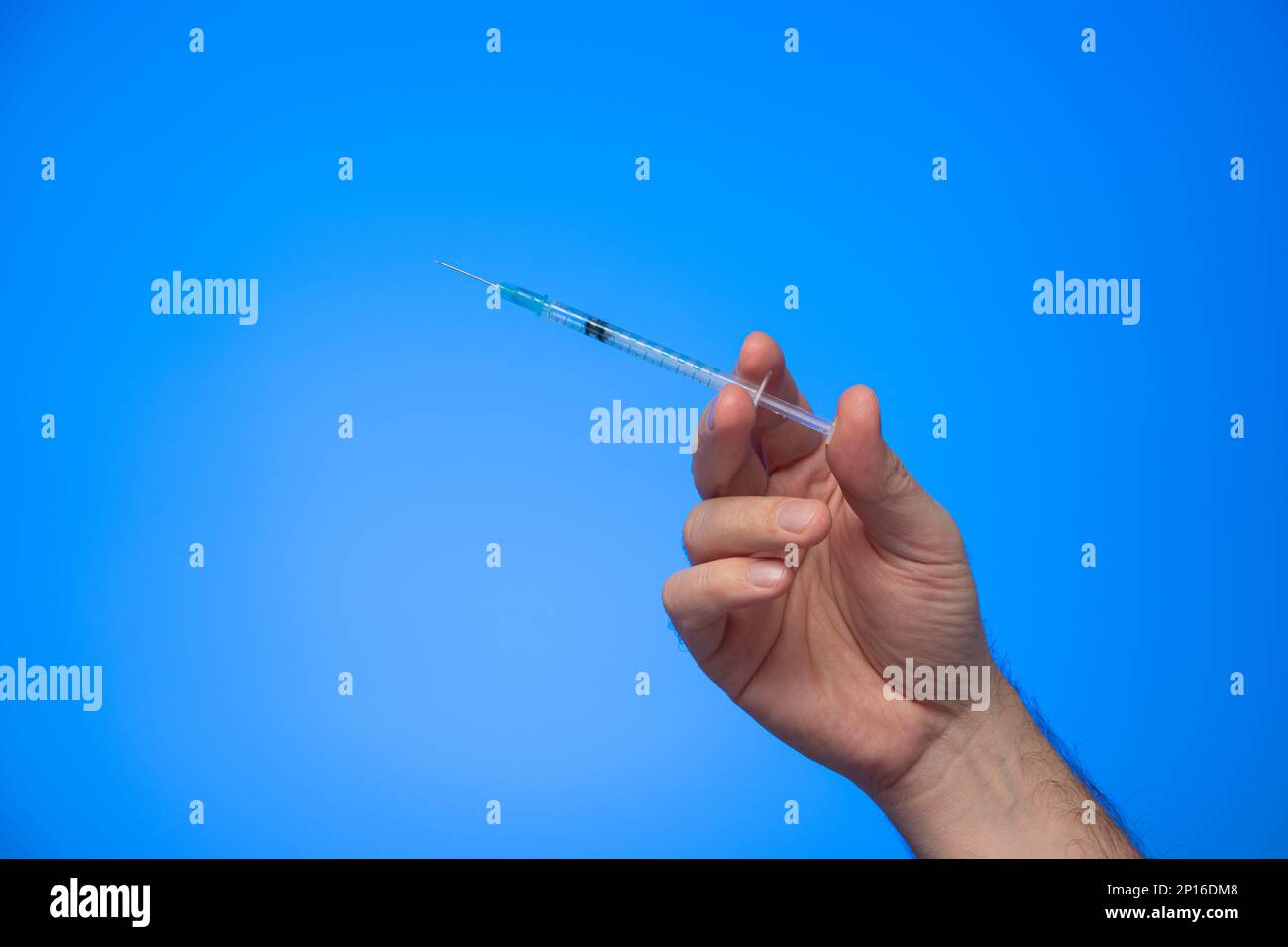 Disposable syringe with needle held in hand by Caucasian male hand ...