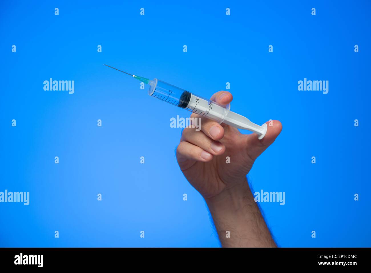 Disposable syringe with needle held in hand by Caucasian male hand ...