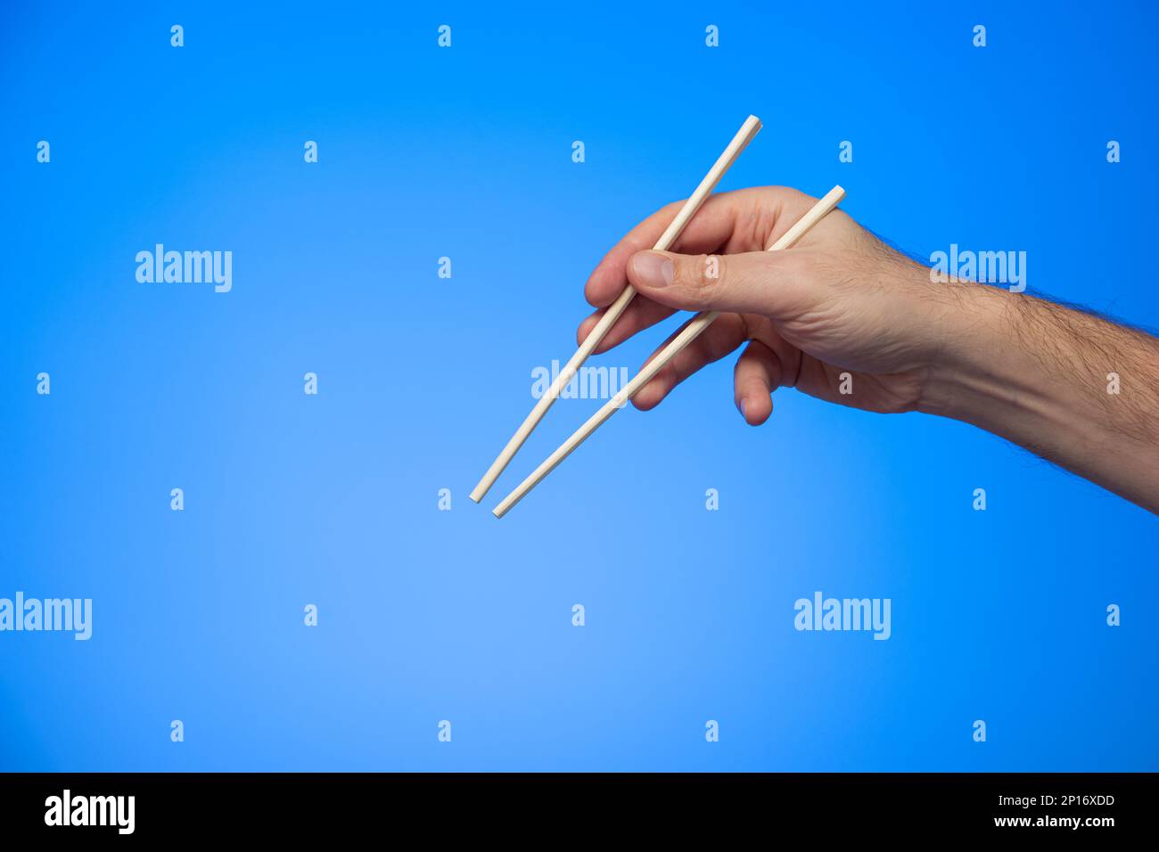 Wooden Asian chop sticks held in hand by Caucasian male hand studio ...