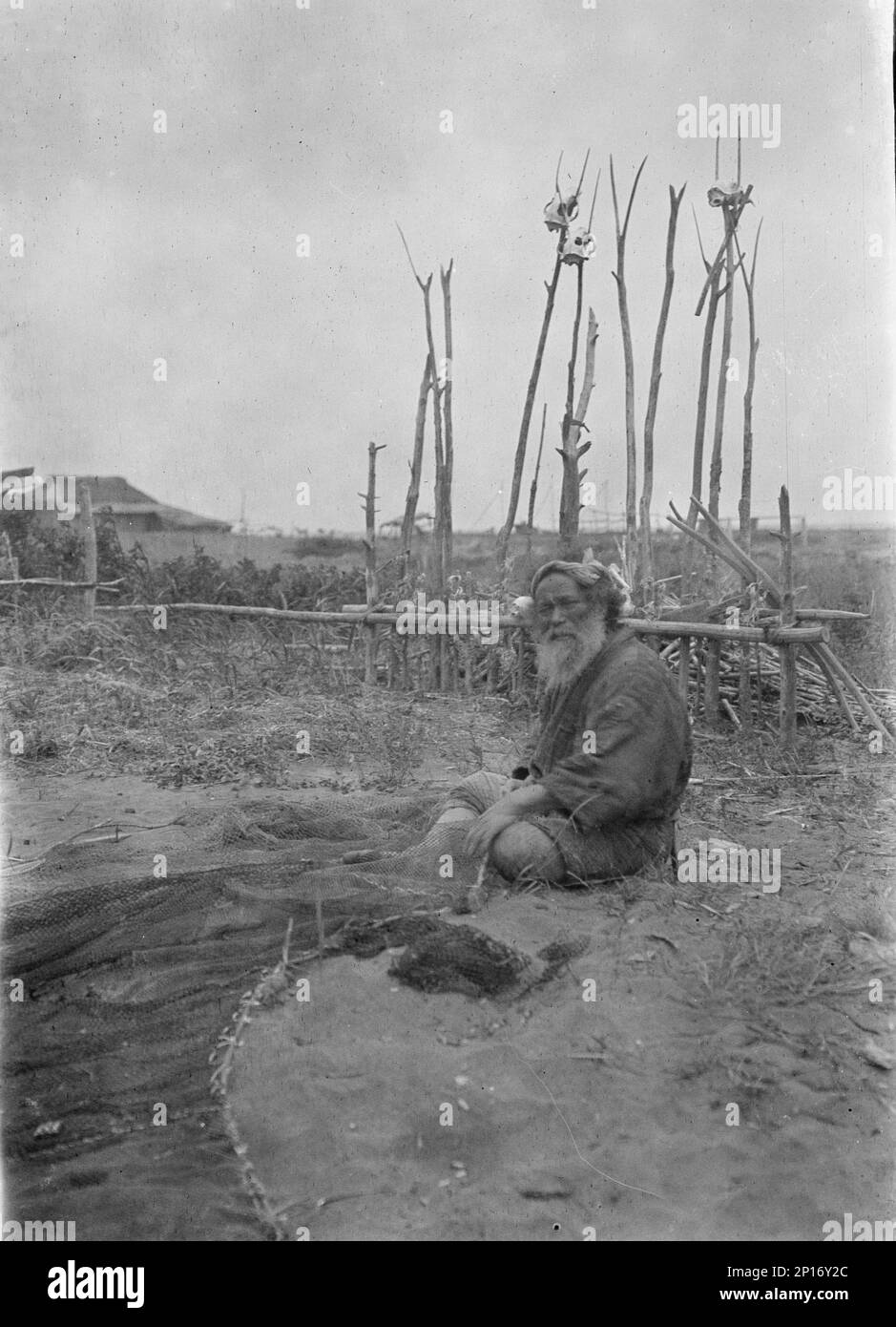 Seated Ainu man working on fishing nets, 1908 Stock Photo - Alamy