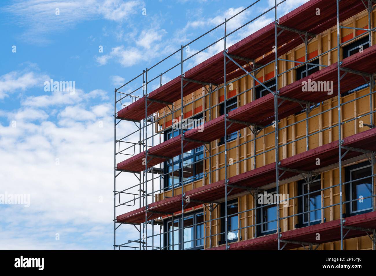 A new wooden panel building surrounded by scaffolding. Light clouds ...