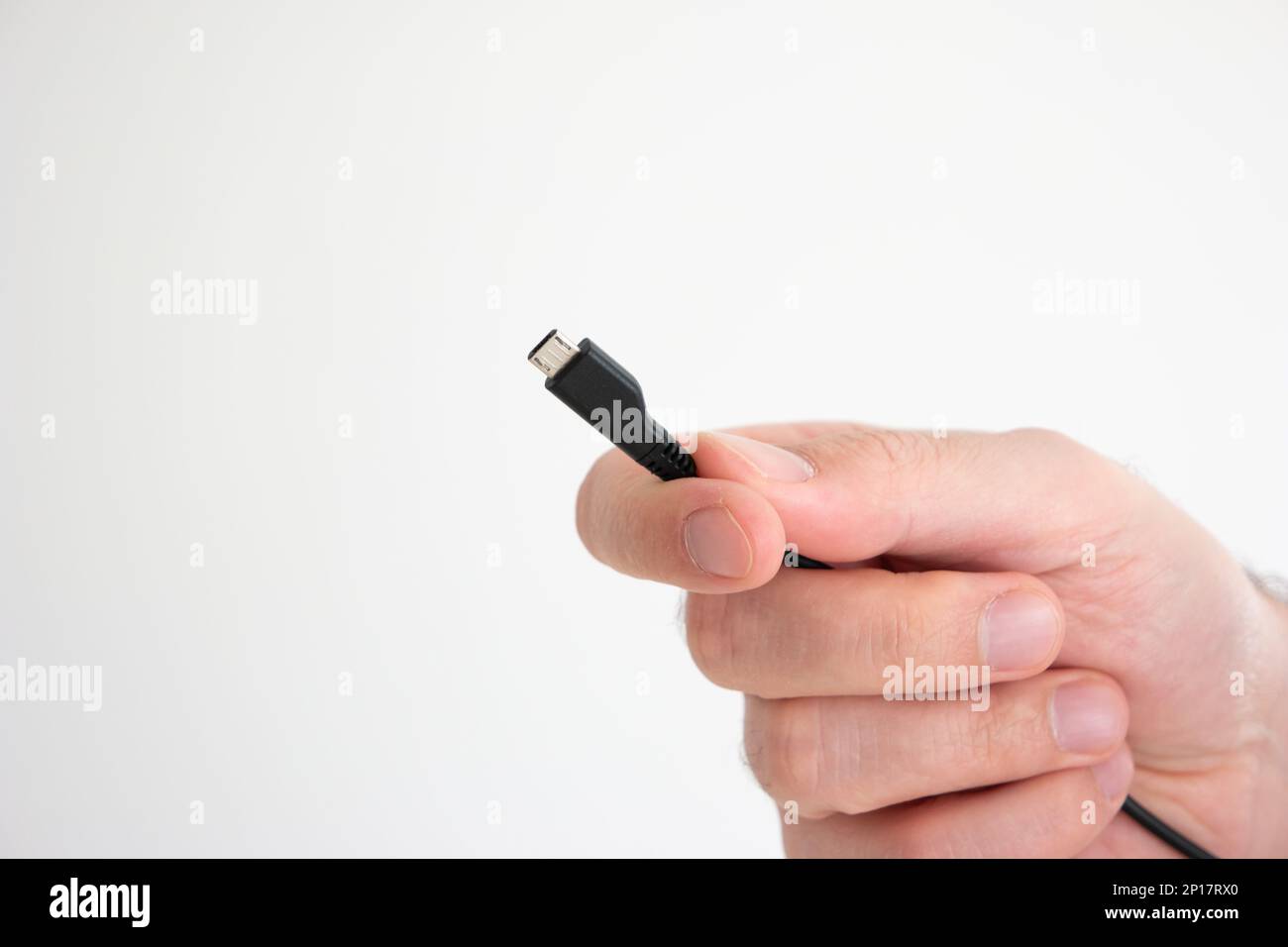 USB cable ad connector held in hand by Caucasian male hand isolated on ...