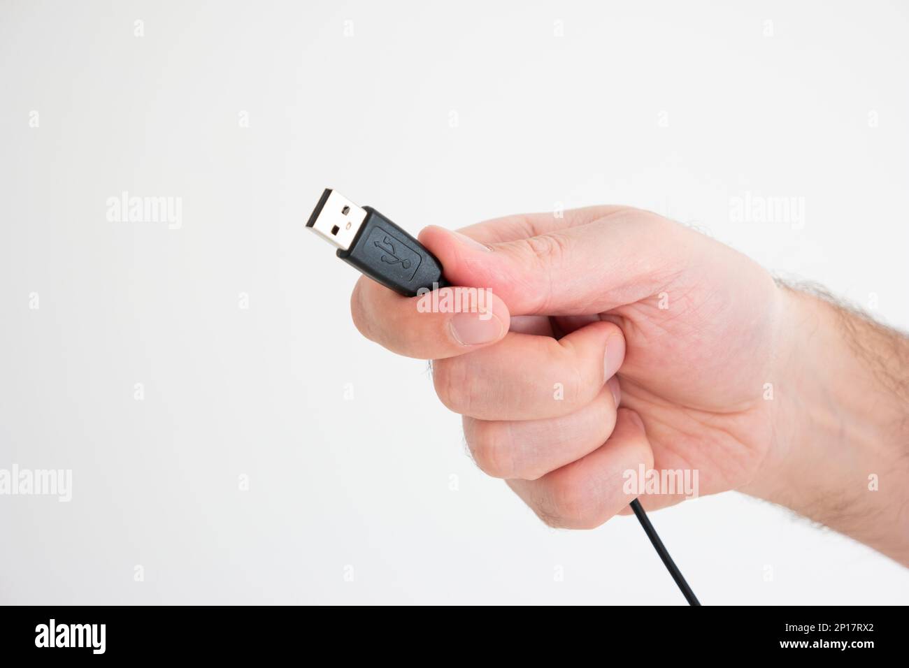 USB cable ad connector held in hand by Caucasian male hand isolated on ...