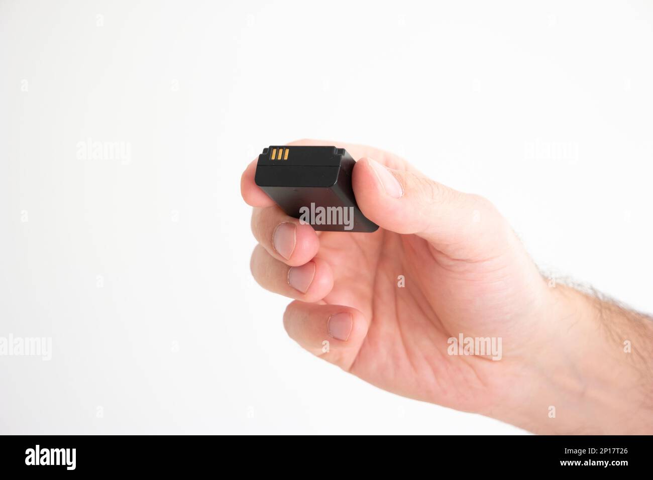 Black square format rechargeable battery held in hand by Caucasian male ...