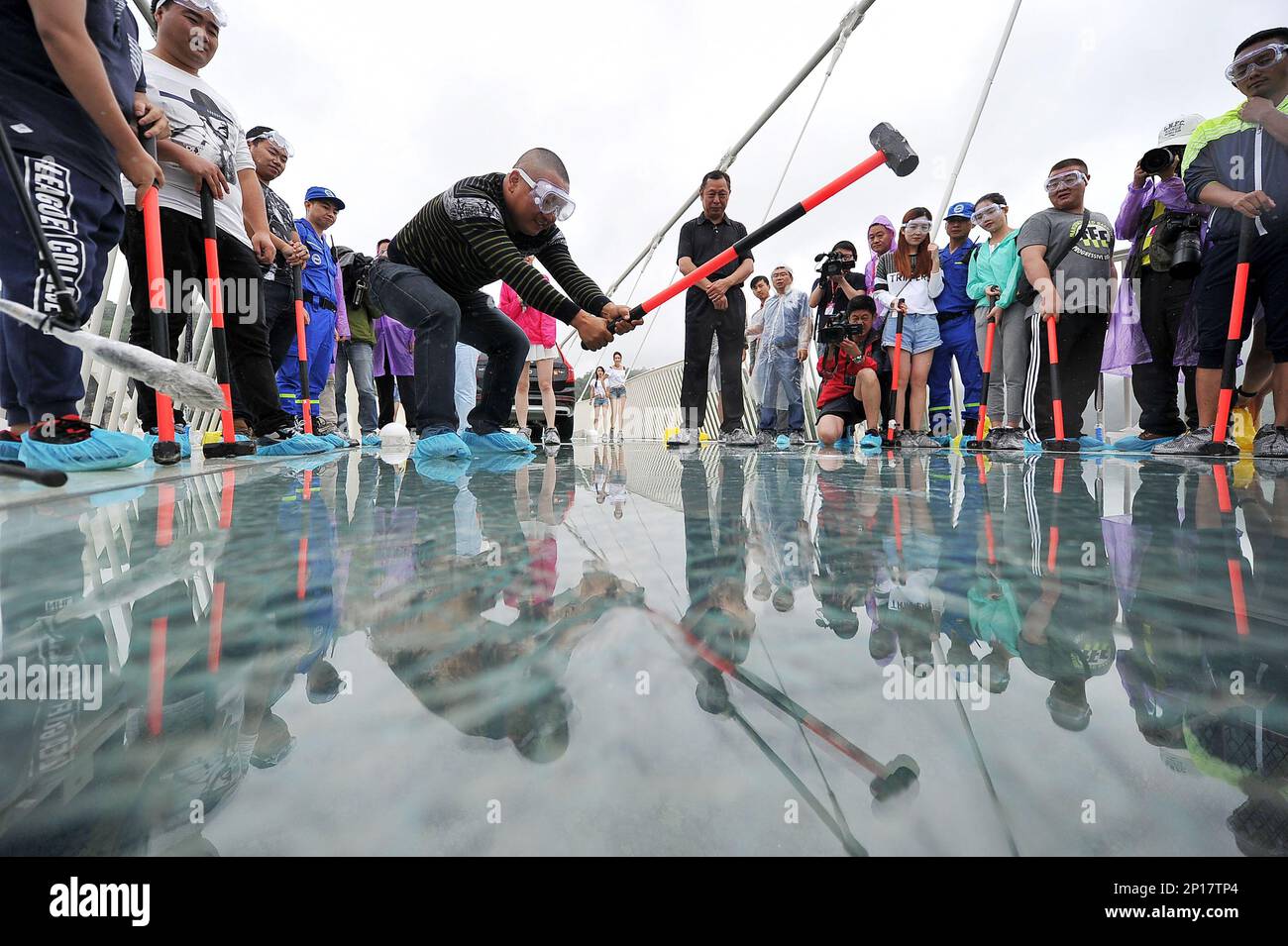 A participant swings a sledgehammer at the floor of glass-bottomed ...