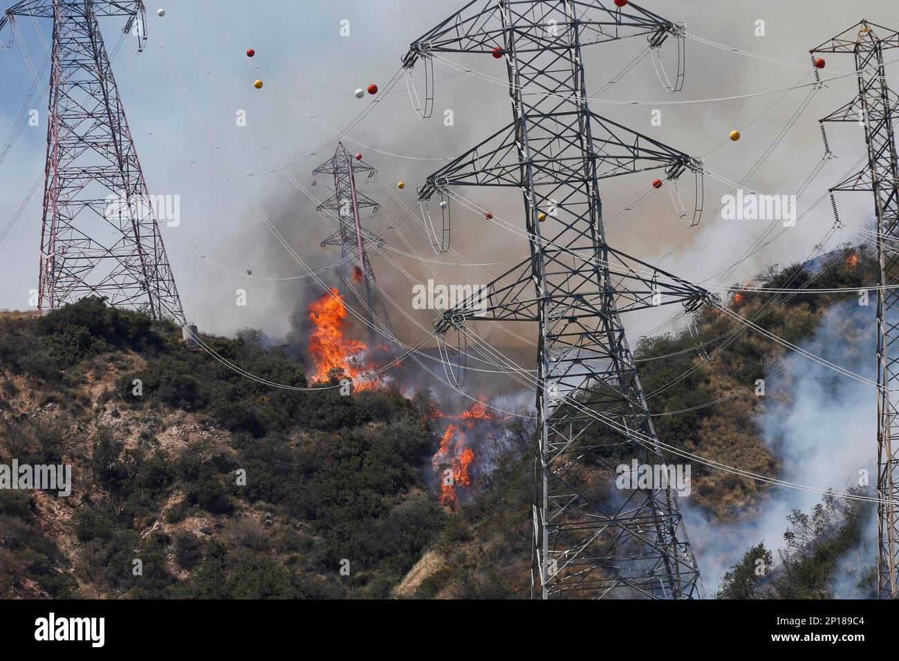 Smoke from wildfires rises from a hillside near power lines outside ...