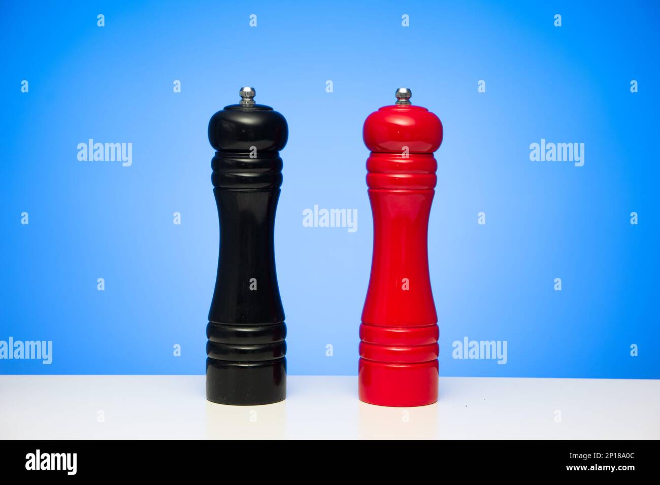 Wooden black pepper and red ground salt grinder mill isolated on blue ...