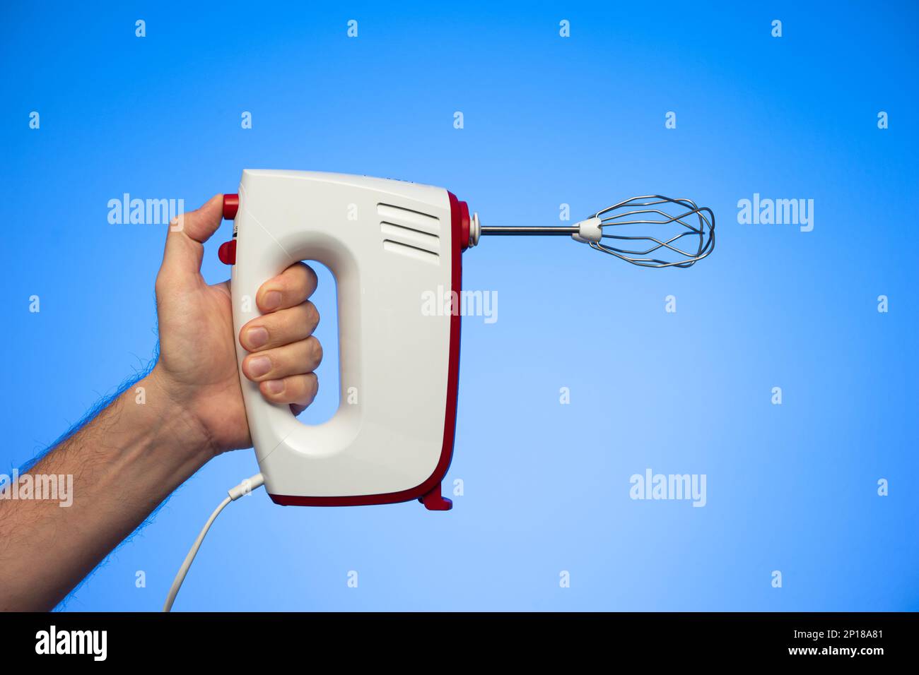 Electric food mixer held in hand by Caucasian male hand studio shot ...