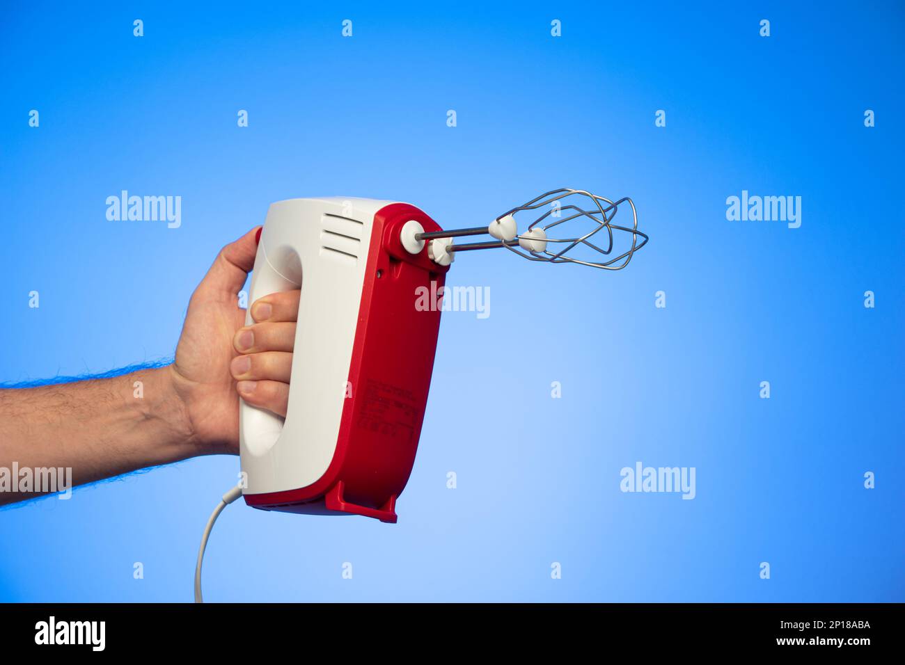 Electric food mixer held in hand by Caucasian male hand studio shot ...