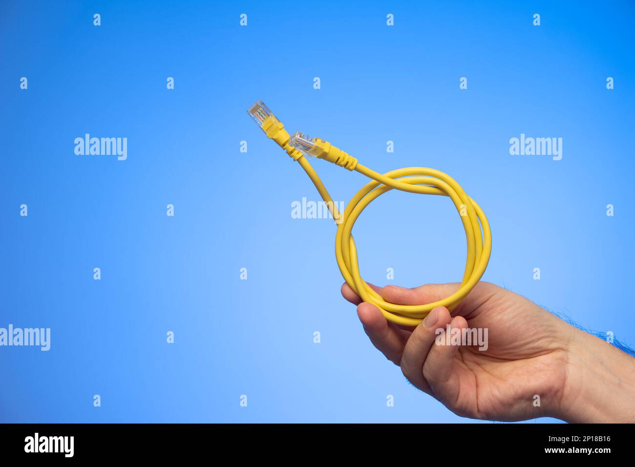 Blue folded Ethernet cable held in hand by Caucasian male hand studio ...
