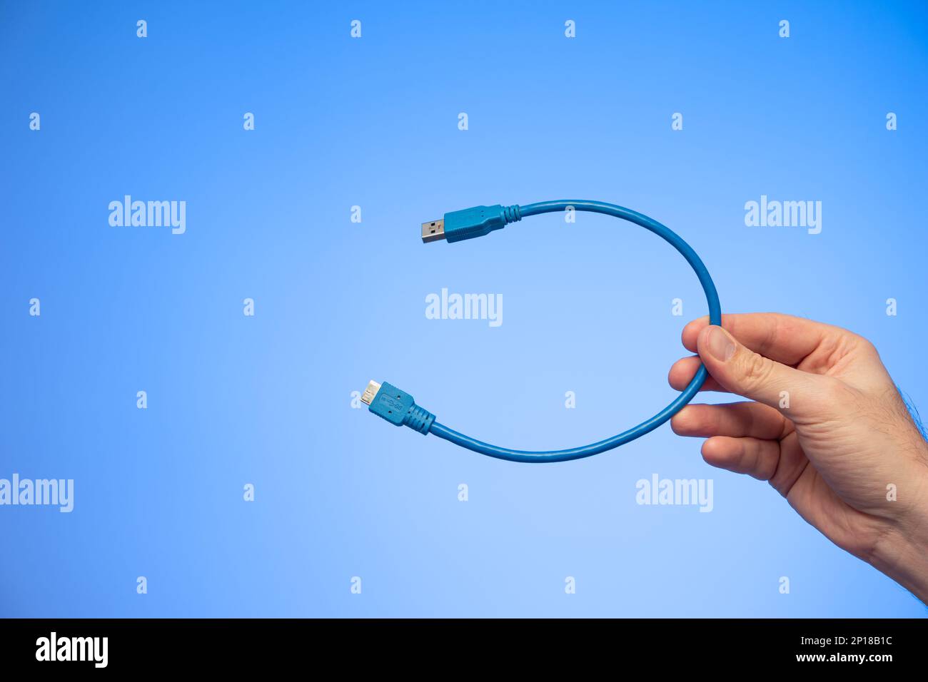 Blue folded HDMI cable held in hand by Caucasian male hand studio shot ...
