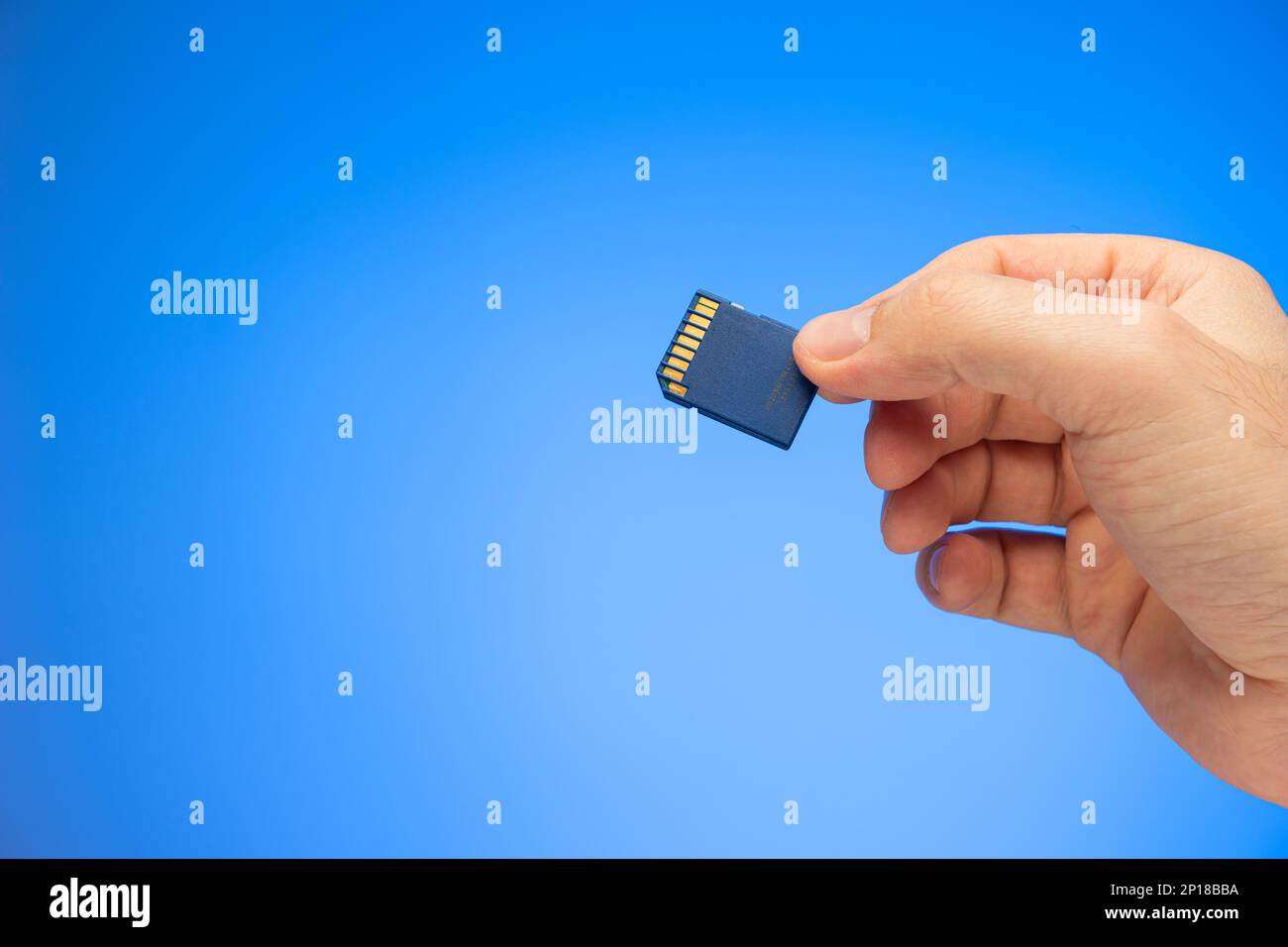 Small plastic SD memory card held in hand by Caucasian male hand studio ...