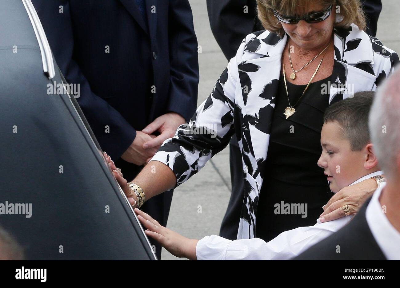 Cathy Howe and a young family member touch the hearse after the funeral ...