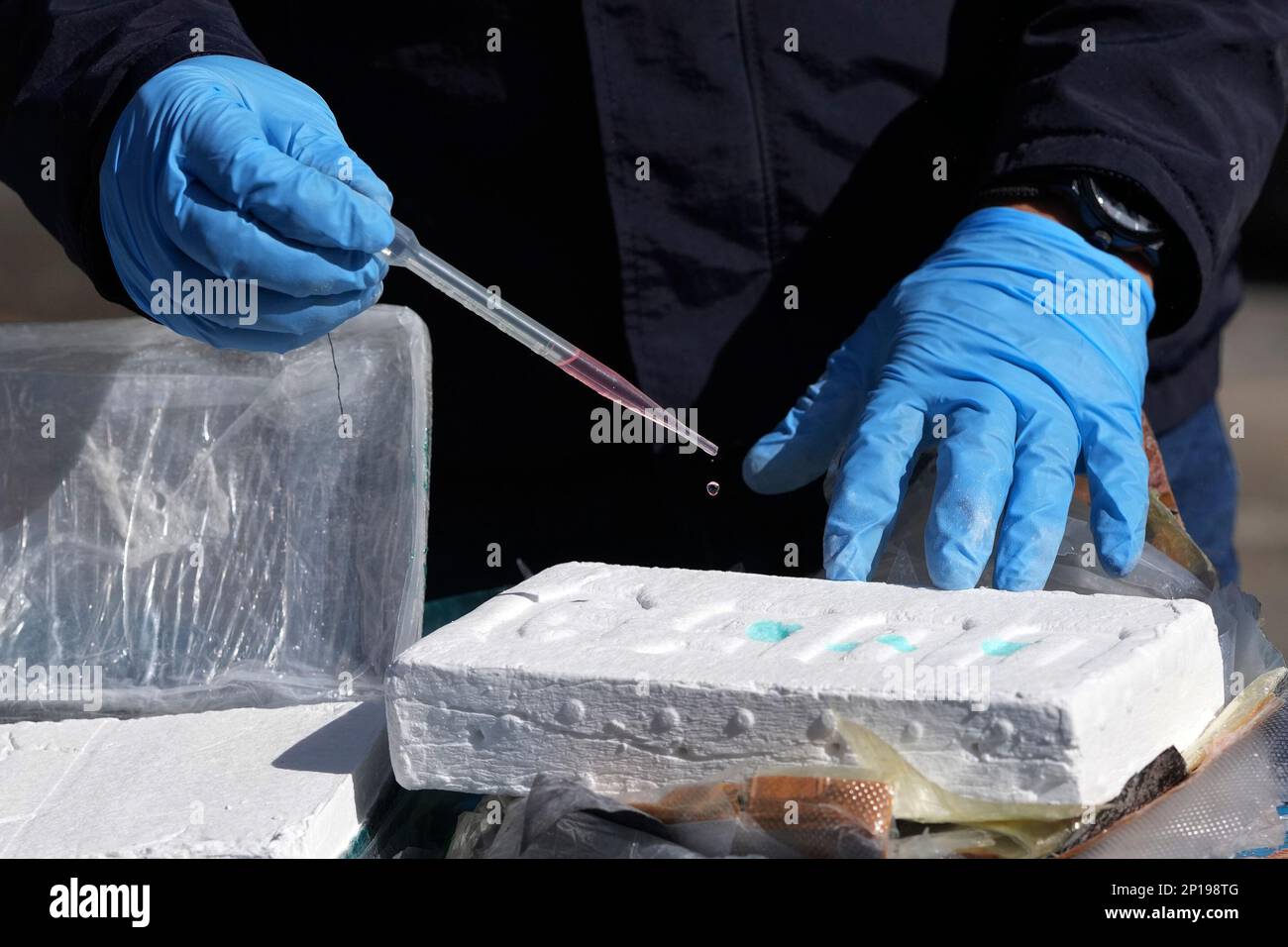 A narcotics officer conducts a chemical analysis to confirm the purity ...