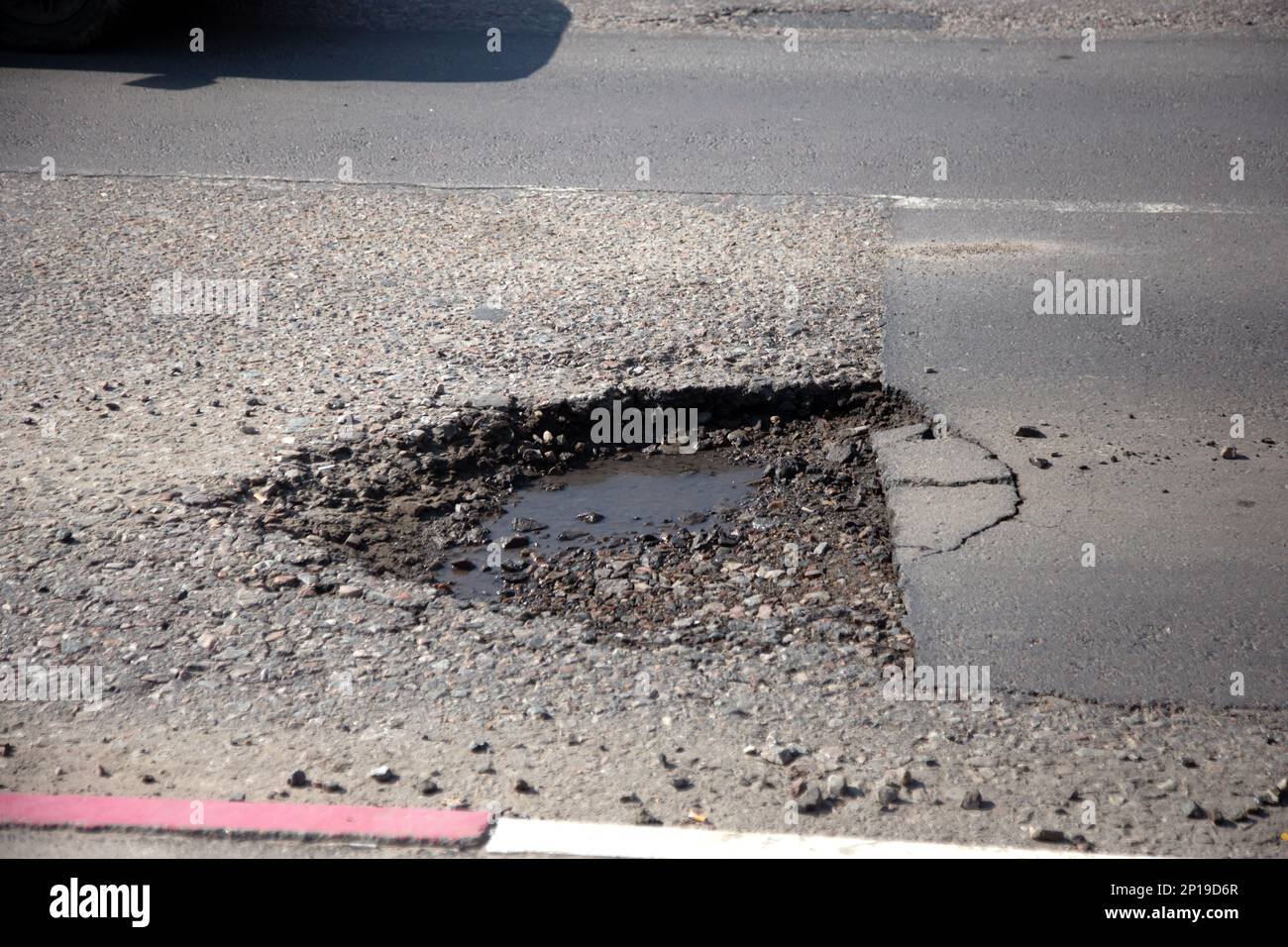 Damaged asphalt road with potholes caused by freezing and thawing ...