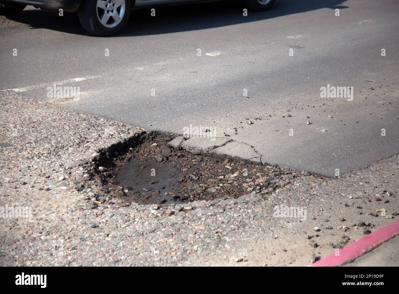 Damaged asphalt road with potholes caused by freezing and thawing ...