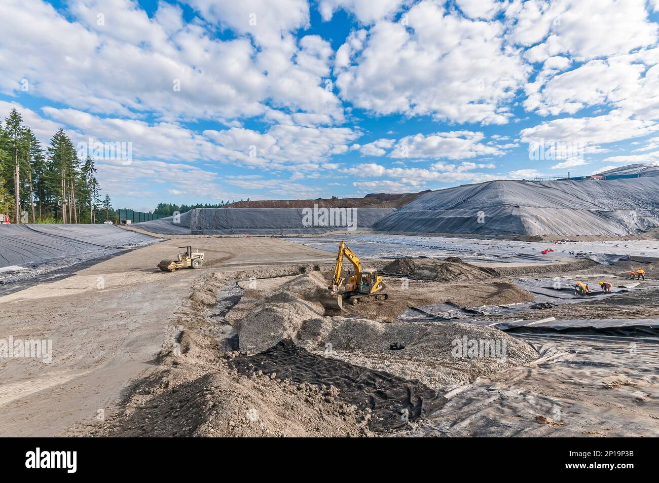 Workers in vast areas of excavation and plastic geomembrane coverings ...