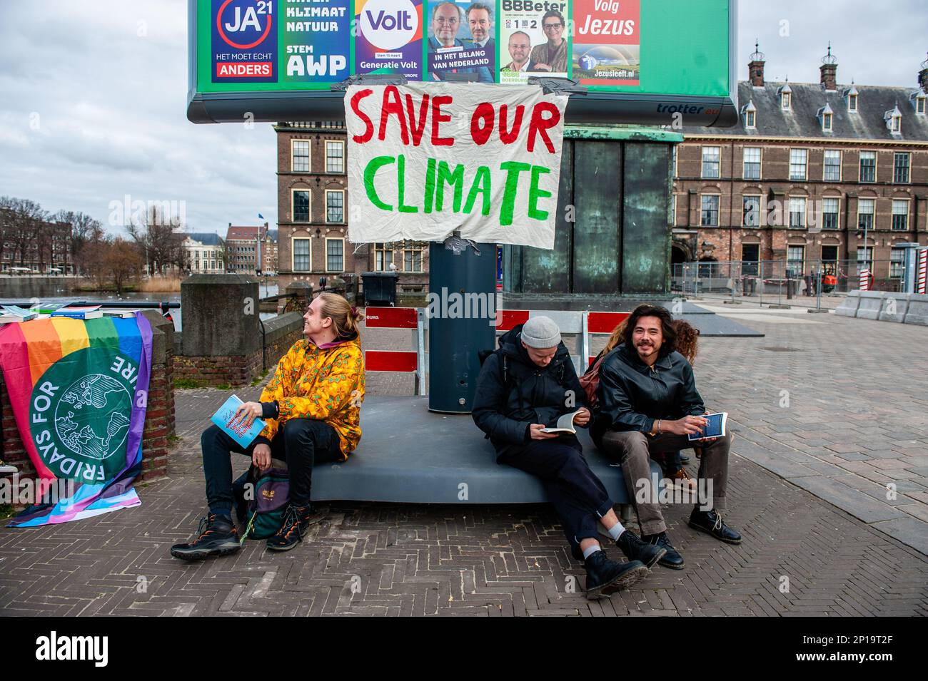 Protesters are seen sitting and reading climate books under a billboard ...