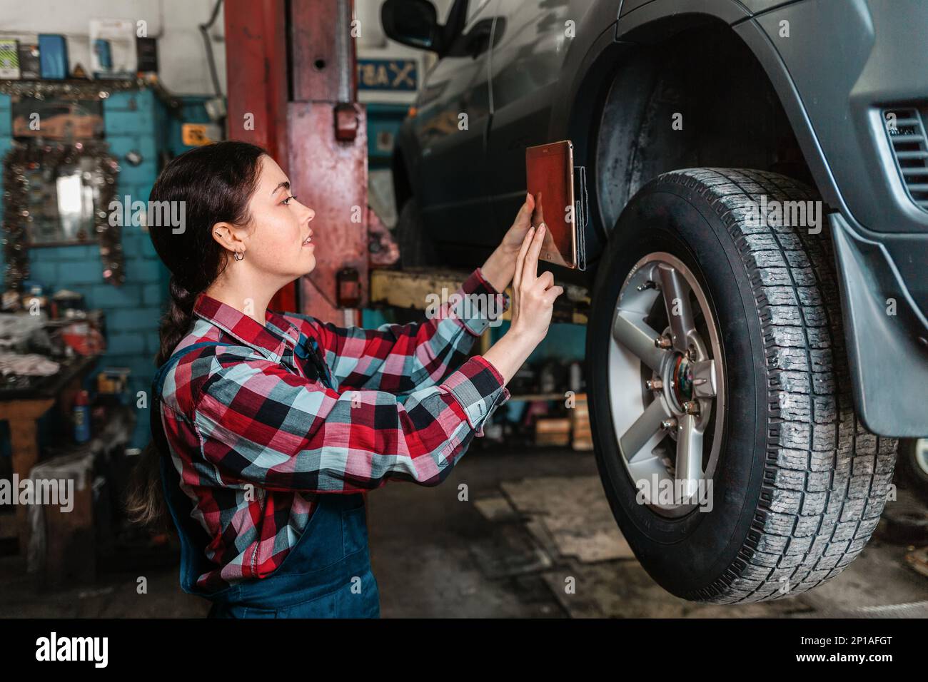 Portrait of a young Caucasian female mechanic, in uniform, using a ...