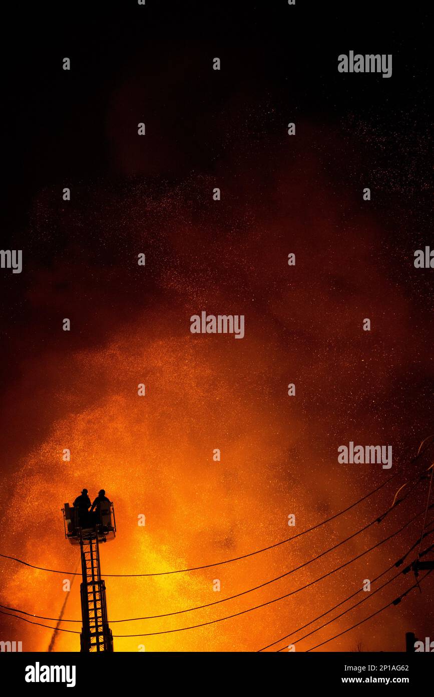 Fire fighters on high ladder fighting fire at night Stock Photo - Alamy