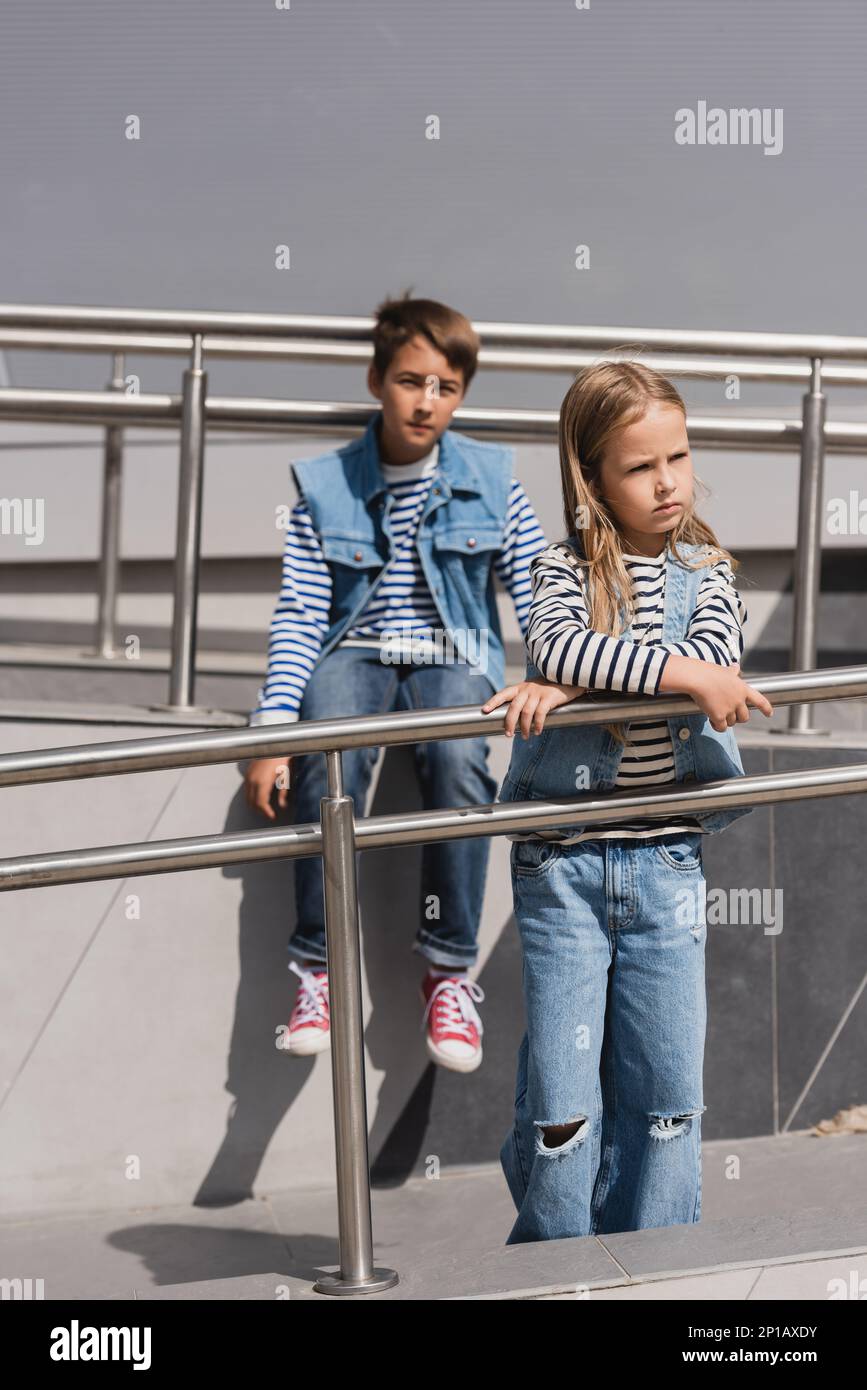 well dressed children in casual denim attire posing near metallic ...