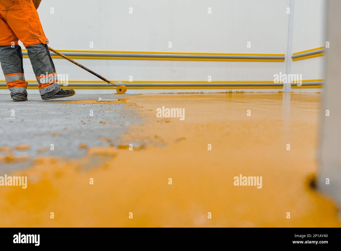 Professional construction worker applying floor paint or a new layer ...