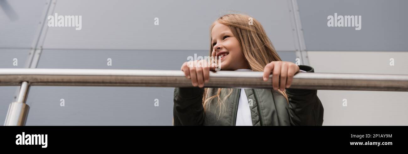 low angle view of cheerful and well dressed preteen girl in bomber ...
