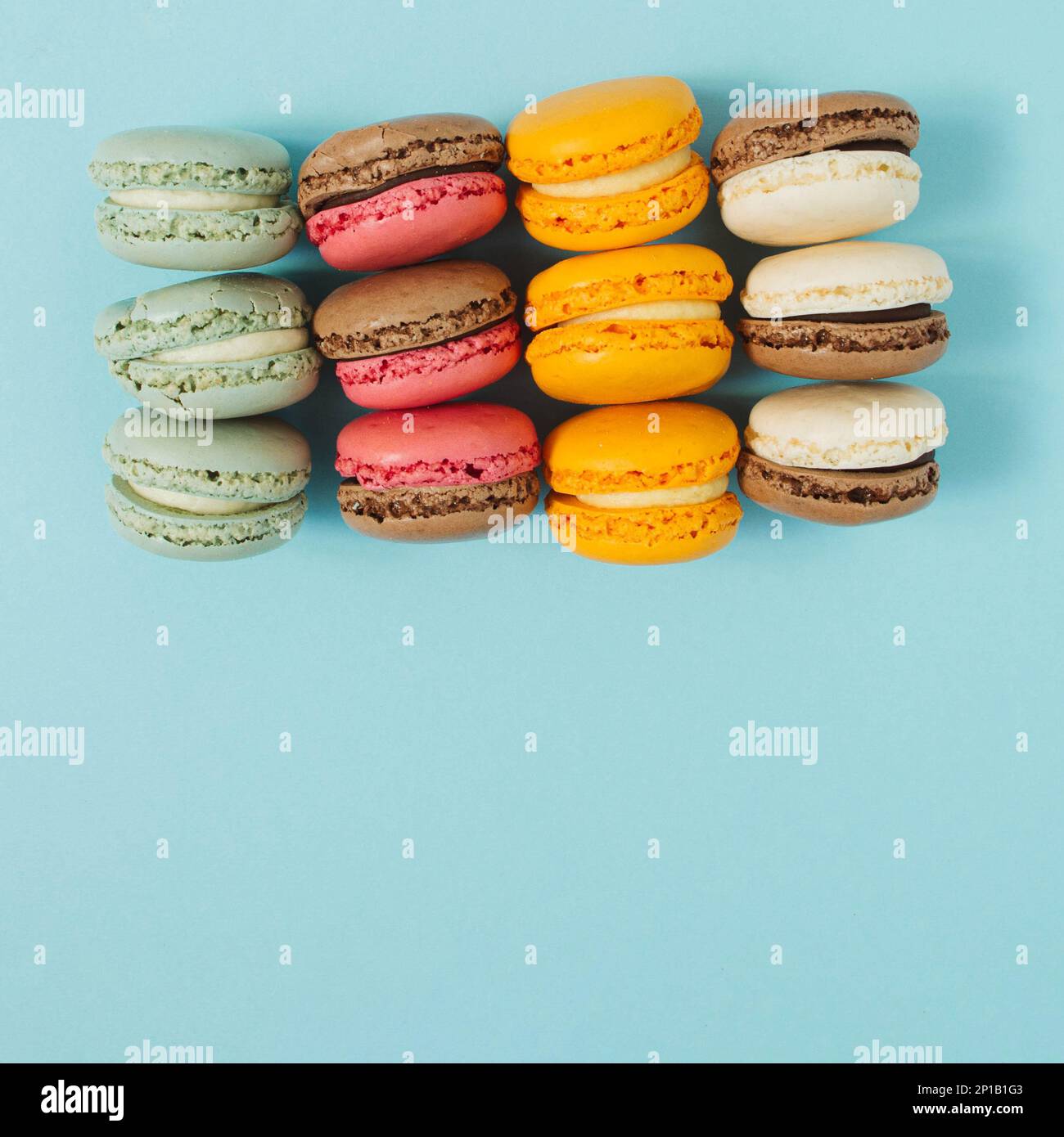 Colorful macarons arranged in a stack on a blue background with plenty ...