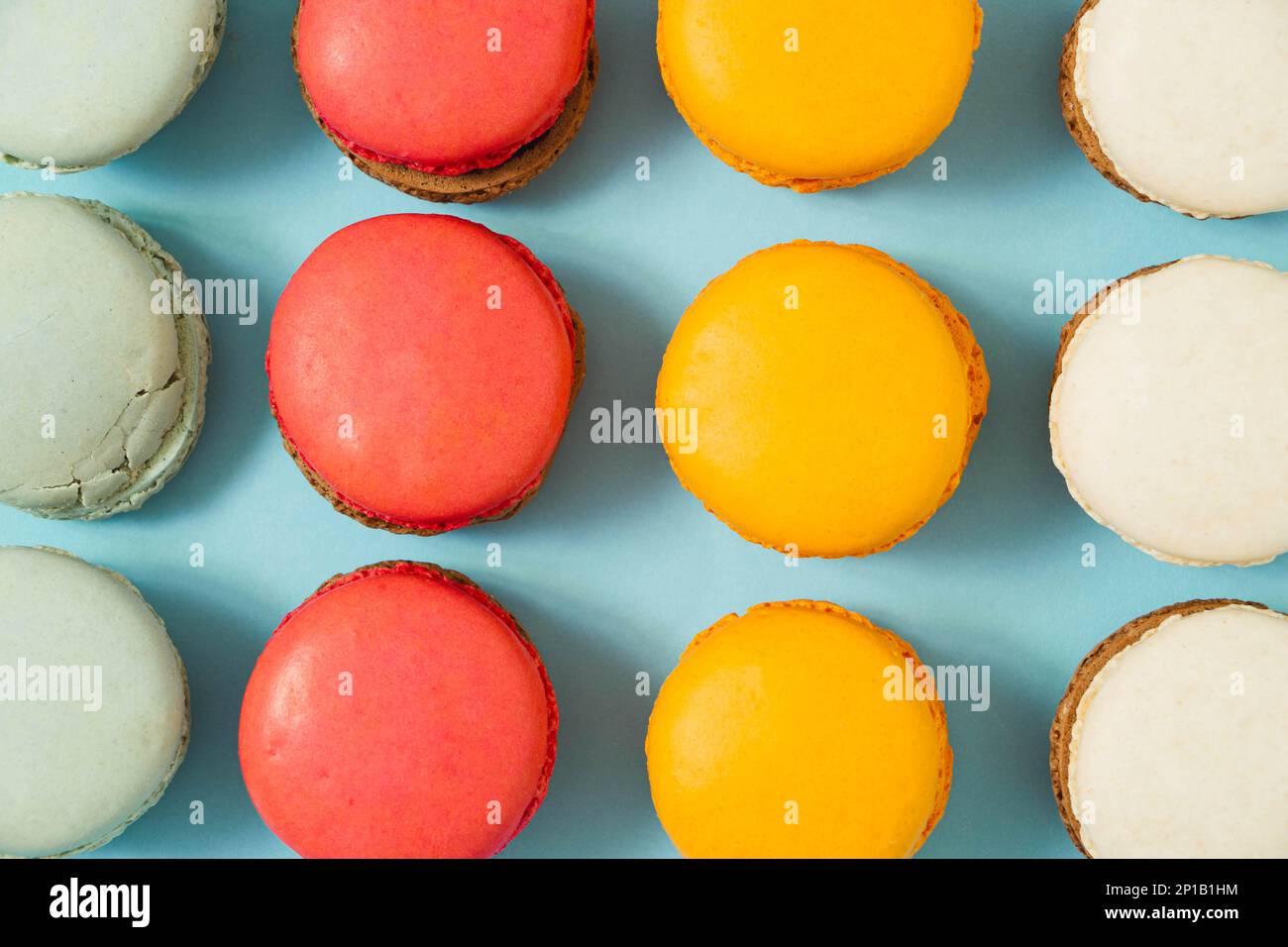 An array of colorful macarons arranged in a neat and tidy pattern atop ...