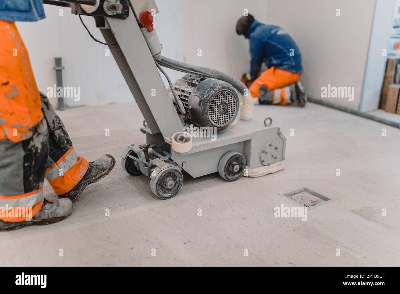 Workers grind the concrete floor at the construction site. Prepares the ...