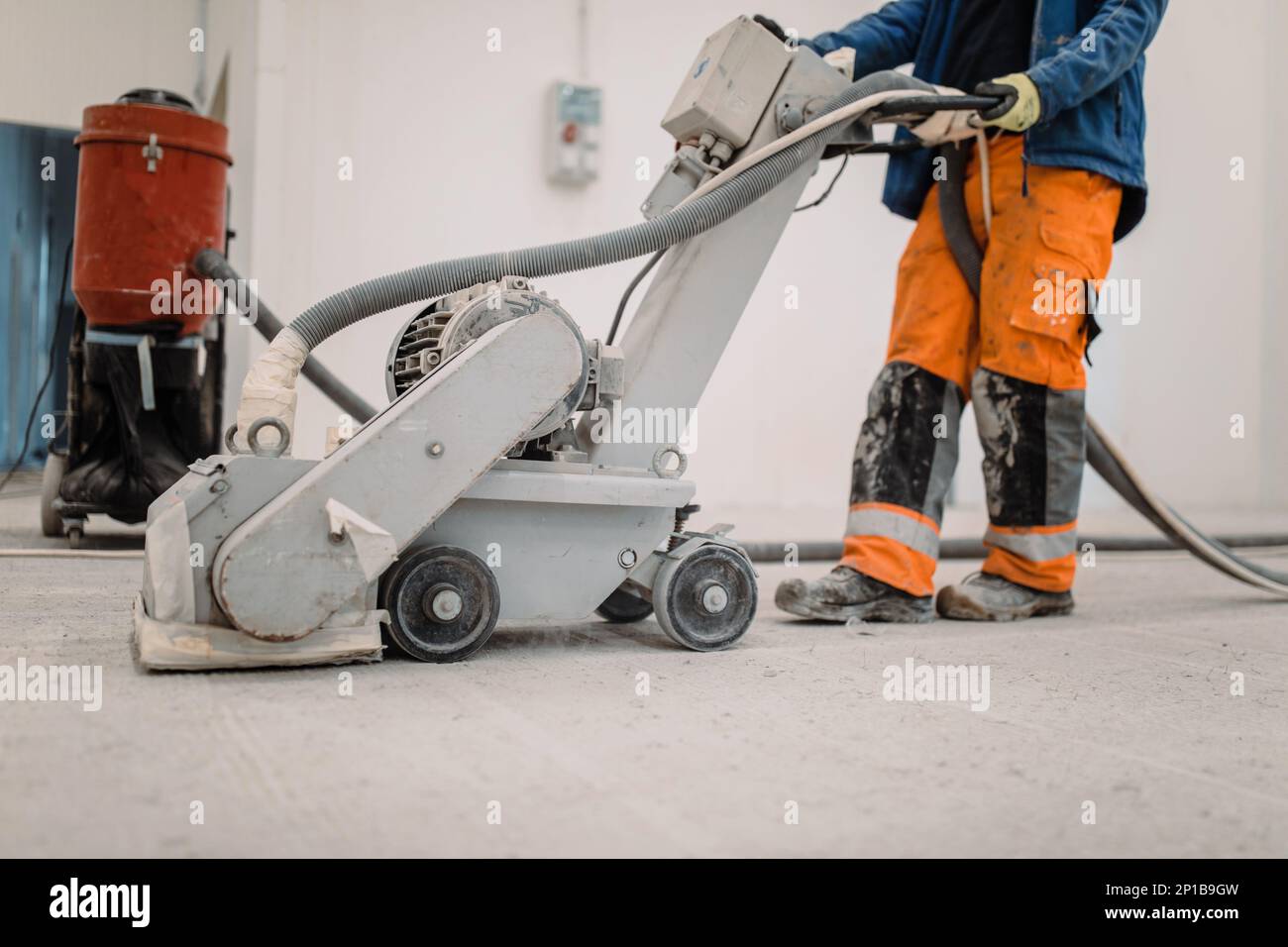 Workers grind the concrete floor at the construction site. Prepares the ...
