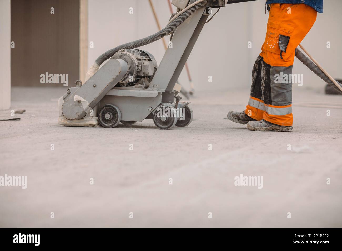 Workers grind the concrete floor at the construction site. Prepares the ...
