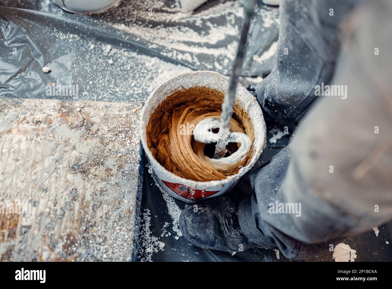 Professional worker mixes two chemical compounds in the metal bucket ...