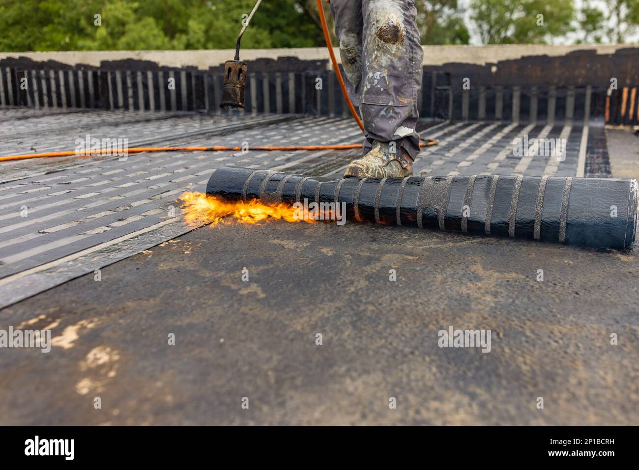 Workers placing a vapor barrier on the roof using a propane gas torch ...