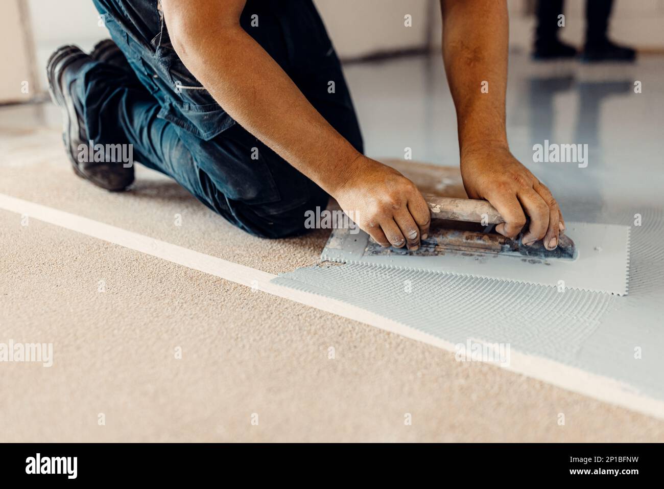 A construction worker apply grey epoxy resin in an industrial hall ...